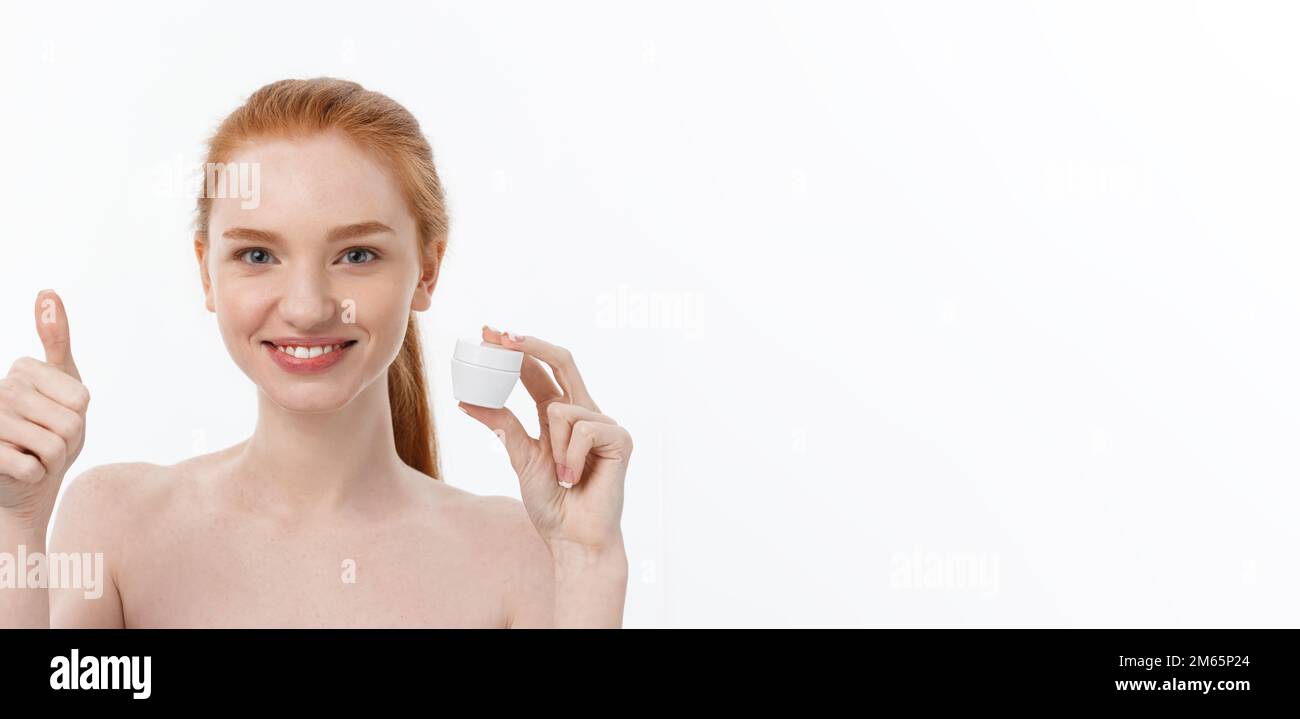 portrait of beautiful woman smiling while taking some facial cream ...