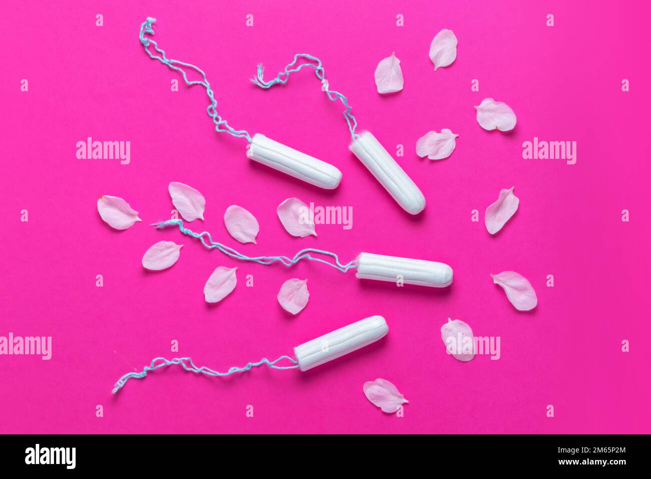 Female tampons with with cherry petals on a pink background. Hygienic ...