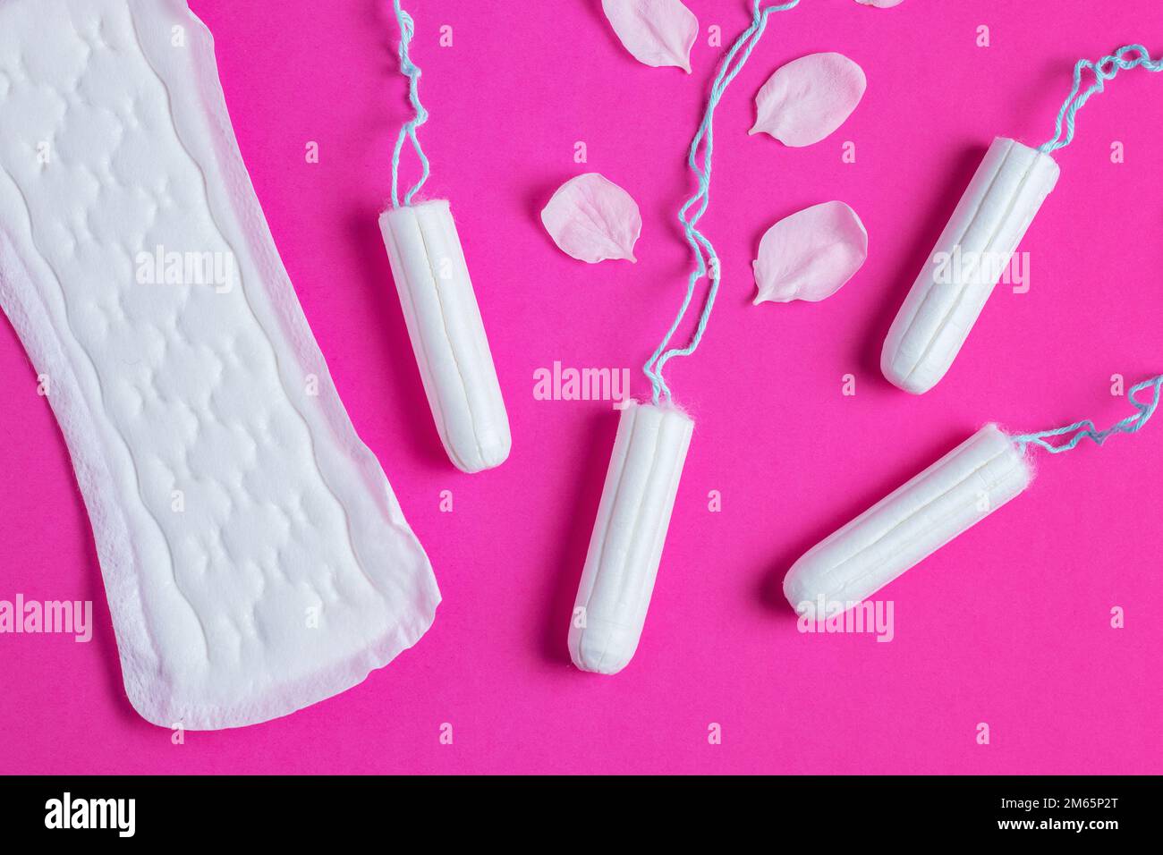 Female tampons with with cherry petals and woman gasket on a pink ...