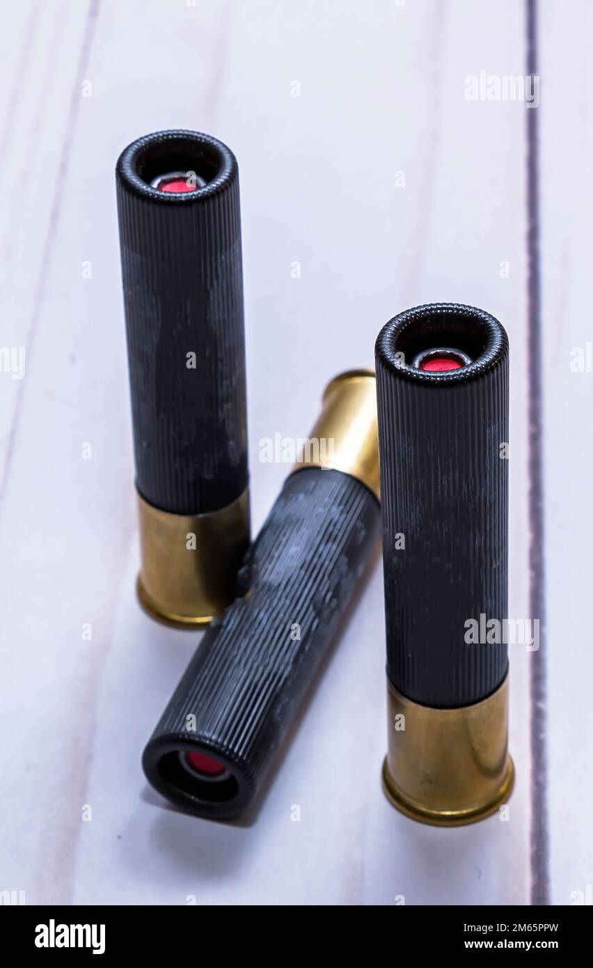 Three black 410 gauge slug shot gun shells on a white wooden background ...