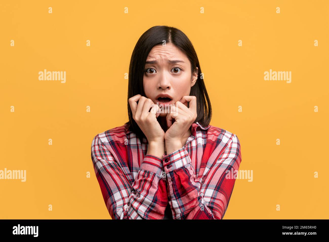 Young asian lady feeling scared, touching cheeks with hands and looking ...