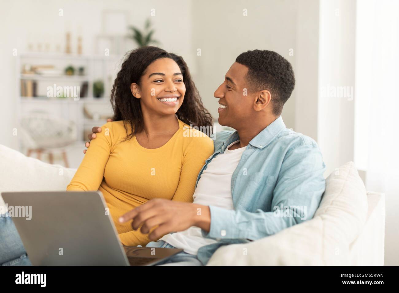 Smiling millennial african american man look at woman use laptop for ...