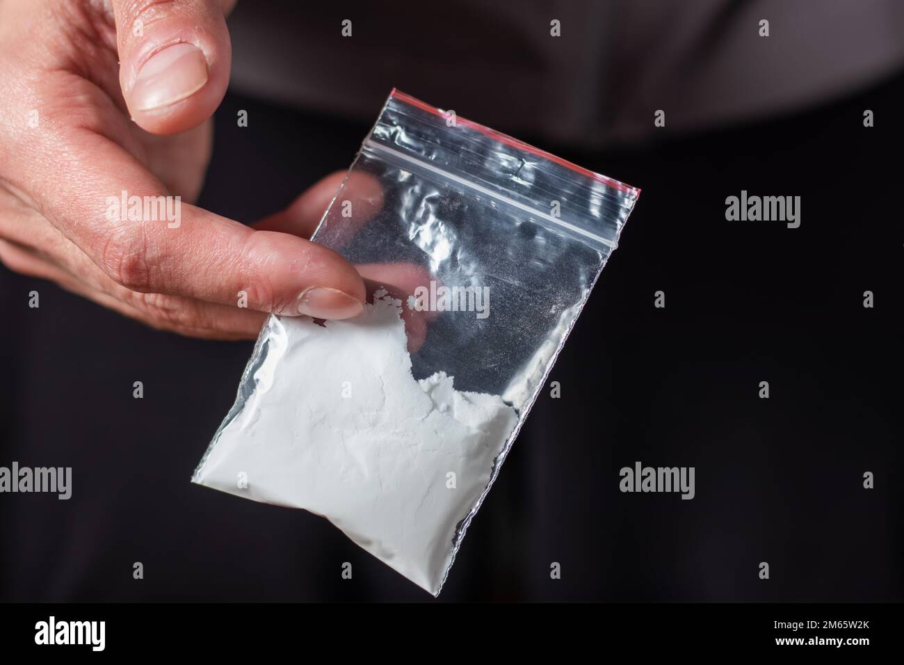 Concept drug addiction. Man hand holds plastic packet or bag with ...