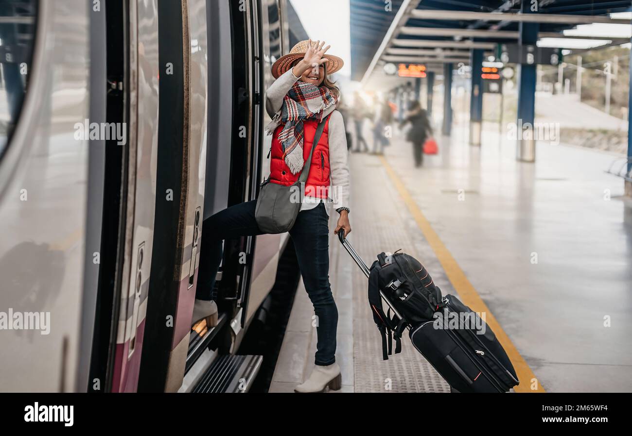 a tourist with hand luggage says goodbye and enters a train waiting at ...
