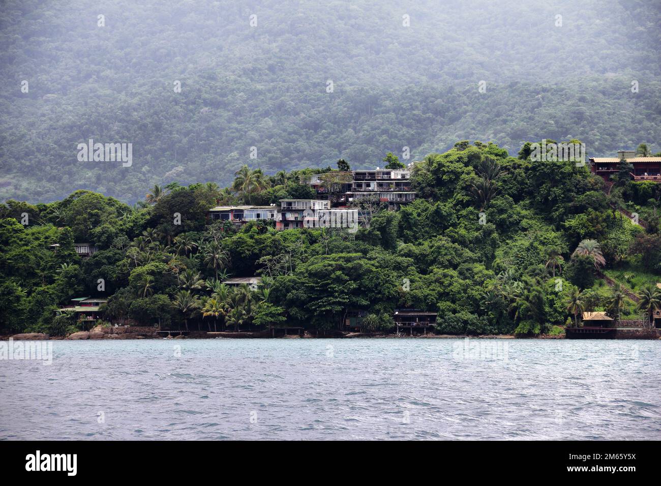 A scenic shot of the sea with lush greenery on the coast in Ilhabella ...
