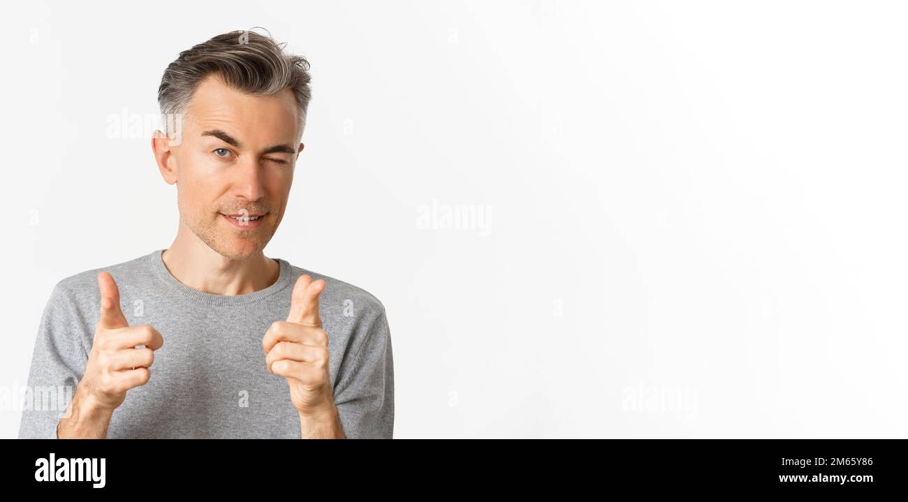 Close-up of handsome cheeky man with gray hair, winking and pointing ...