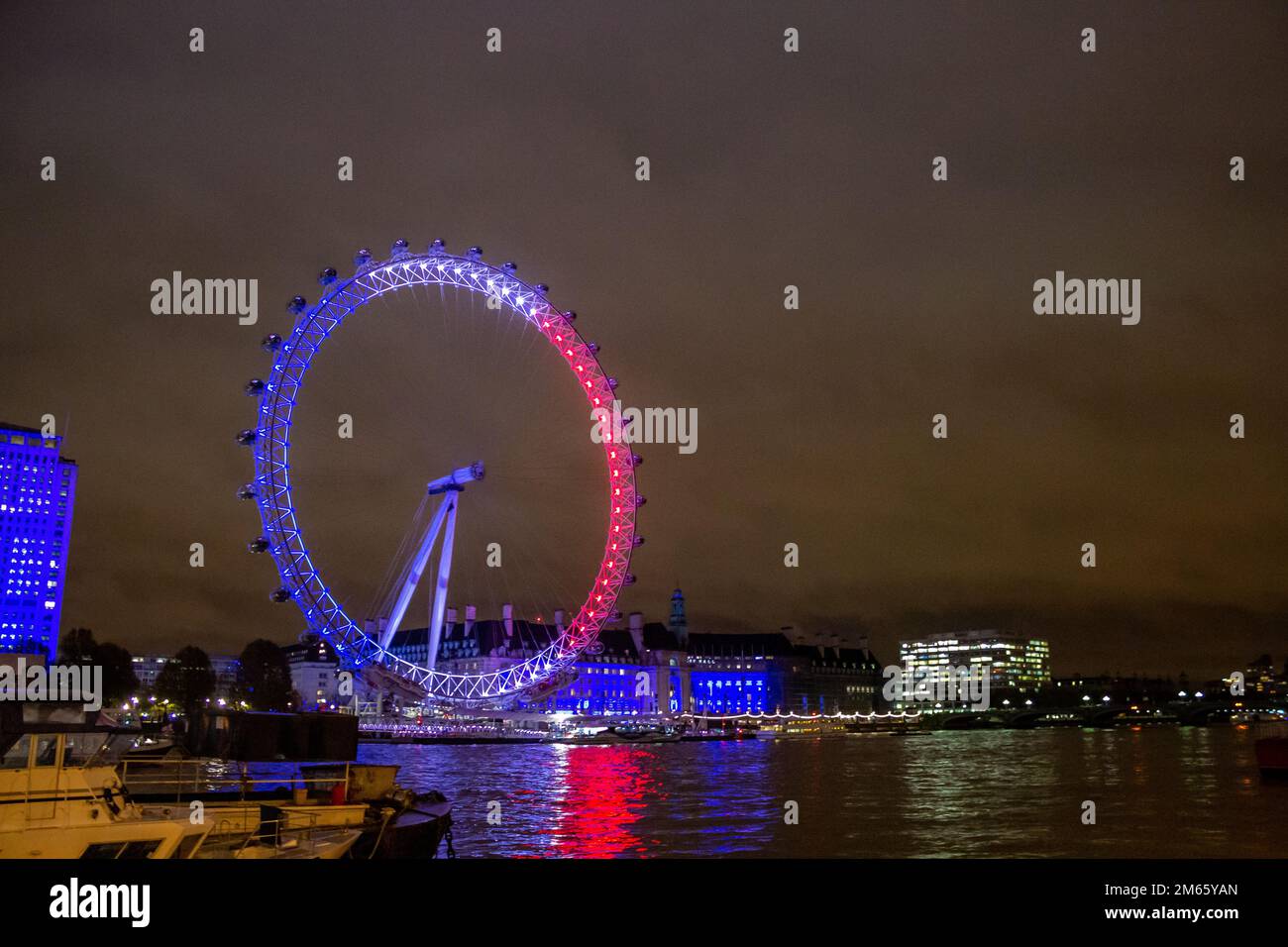The London Eye at night with lights, in the River Thames in London ...
