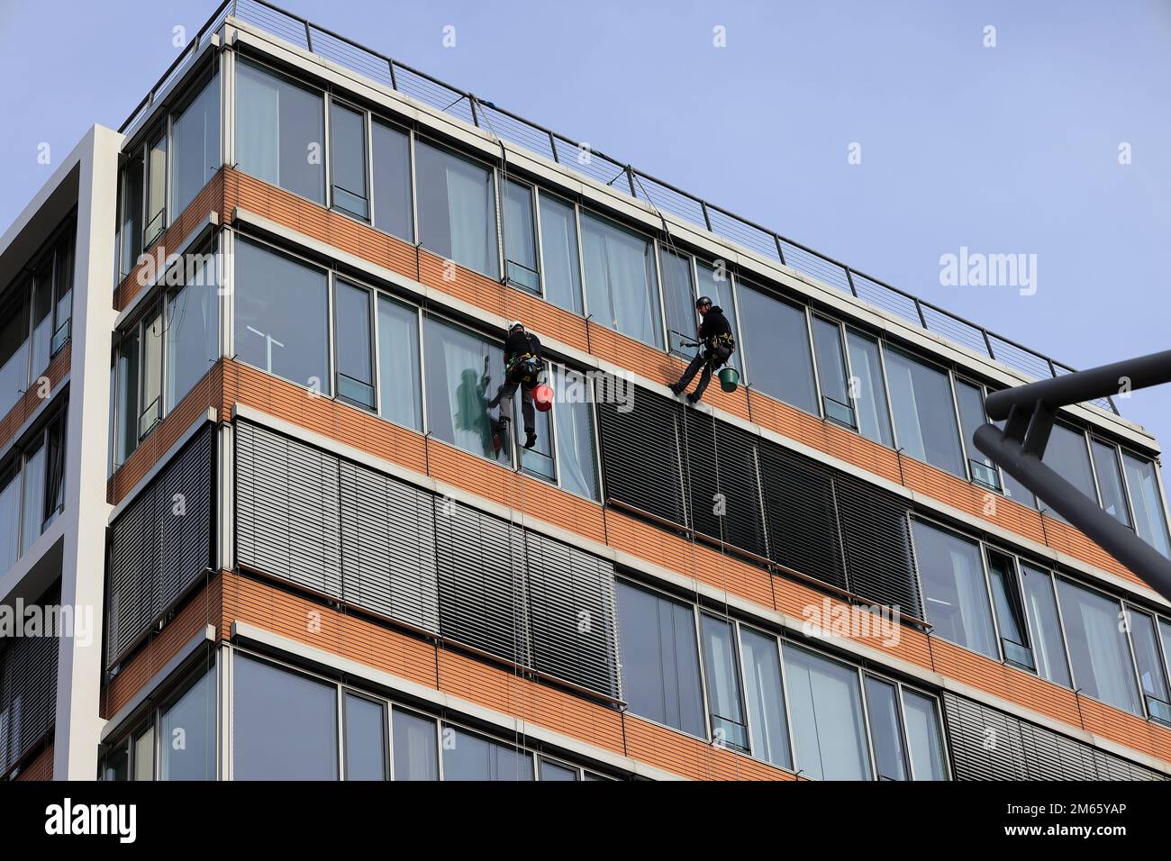 Window cleaners hang on a facade in Hamburg and clean windows Stock ...