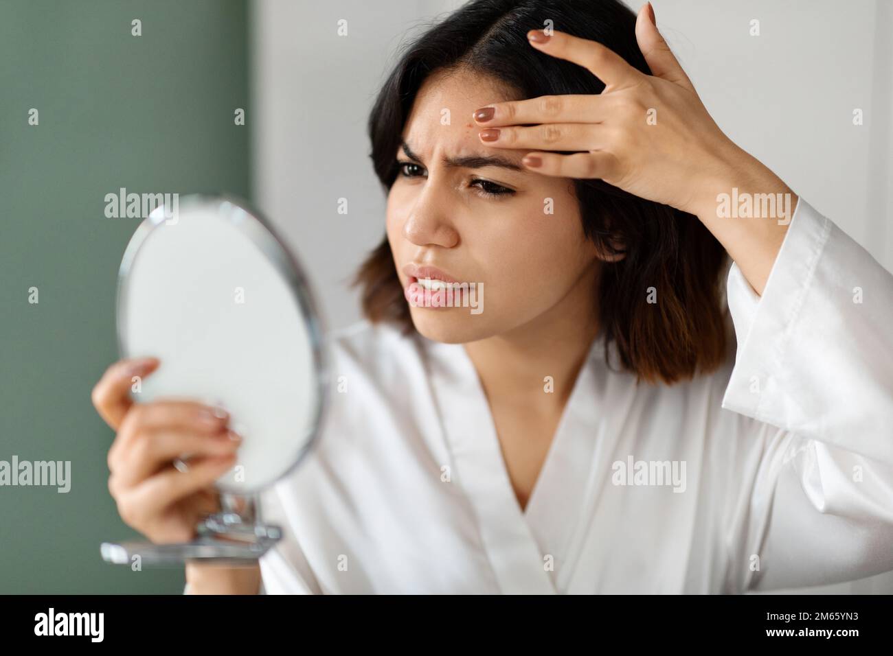 Upset arabic woman looking at hand mirror, checking skin Stock Photo ...