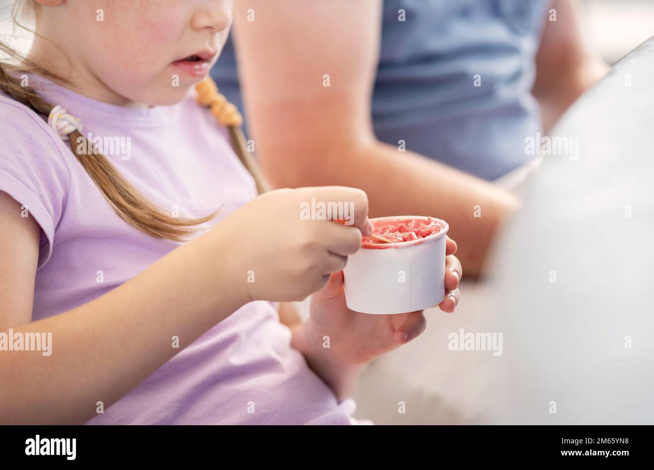 Anonymous elementary school age child girl eating ice cream from a ...