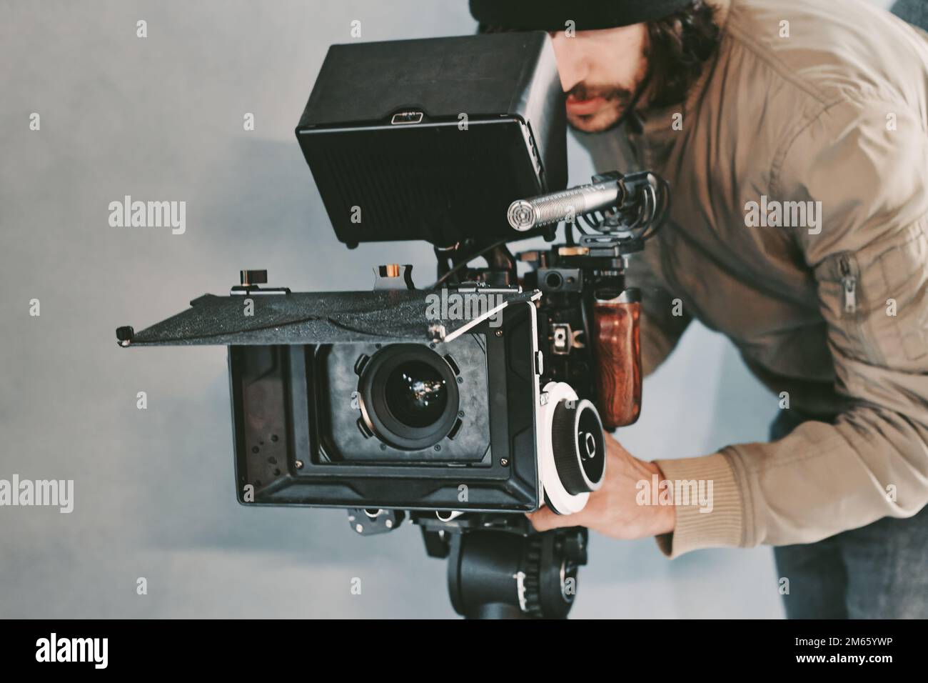 A young male cameraman behind a movie video camera filming on set Stock ...