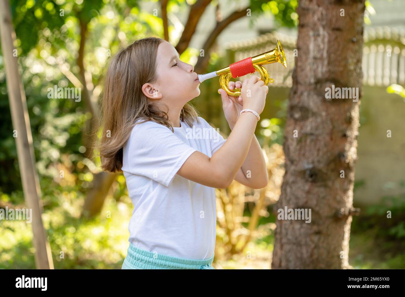 Elementary school age girl playing a toy trumpet prop, holding it in ...