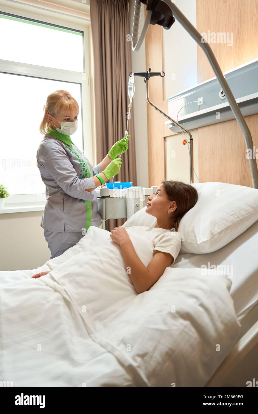 Nurse controls a dropper and communicates with a small patient Stock ...