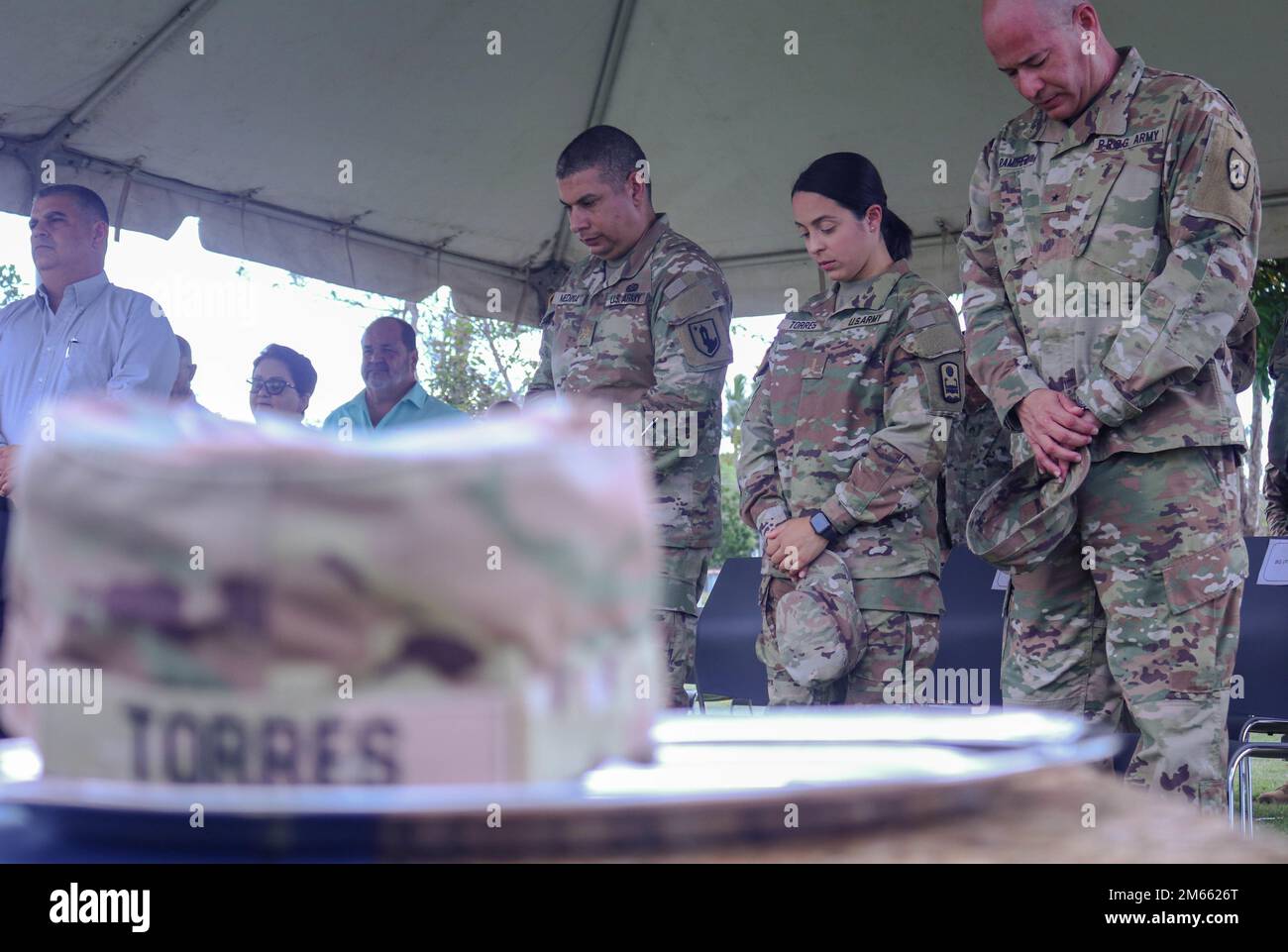 Brig. Gen. Edrick Ramírez, right, high-rank officials, and family bow during the chaplain's ...