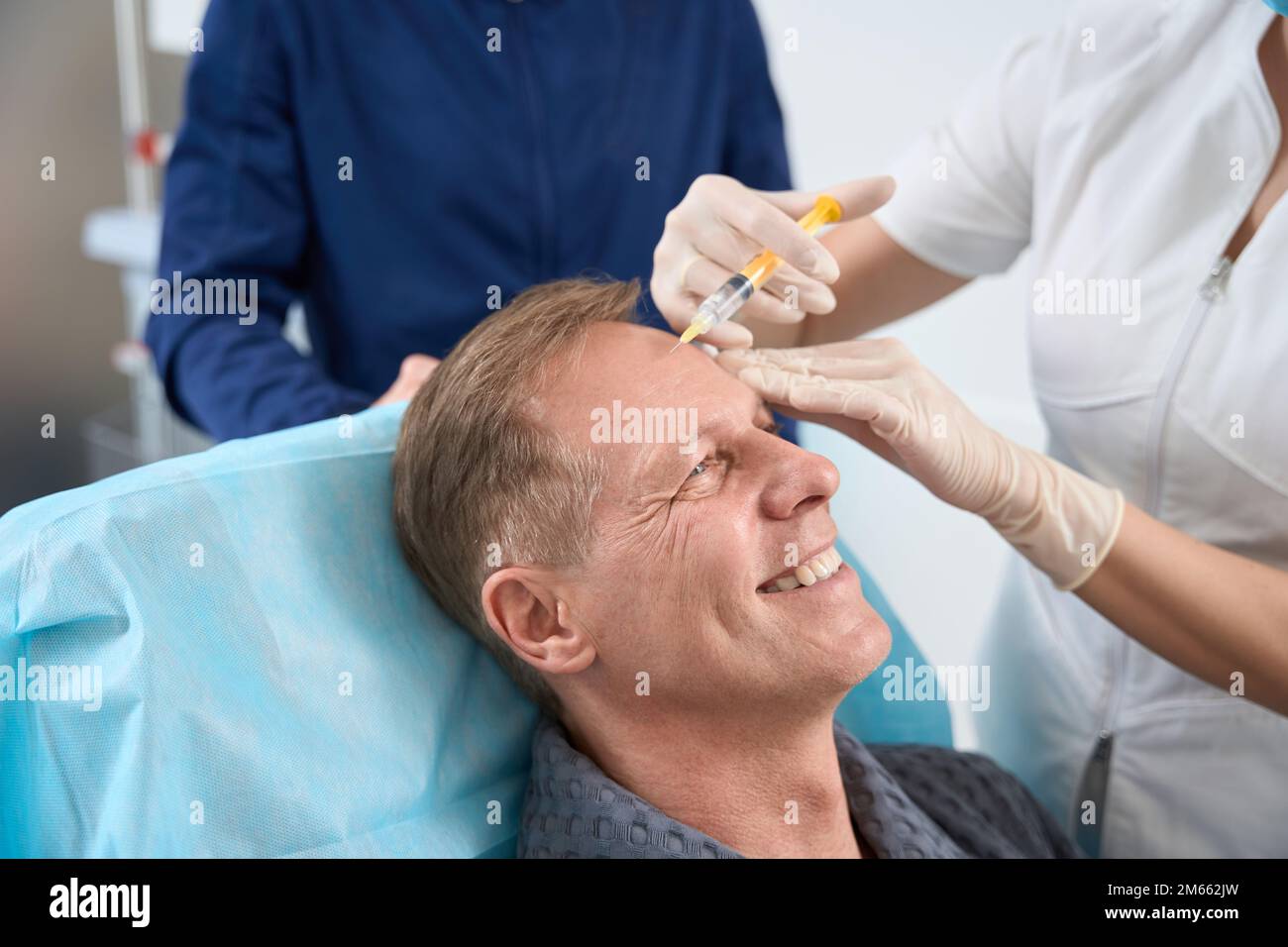 Cheerful man feeling great during skin rejuvenation procedure Stock ...