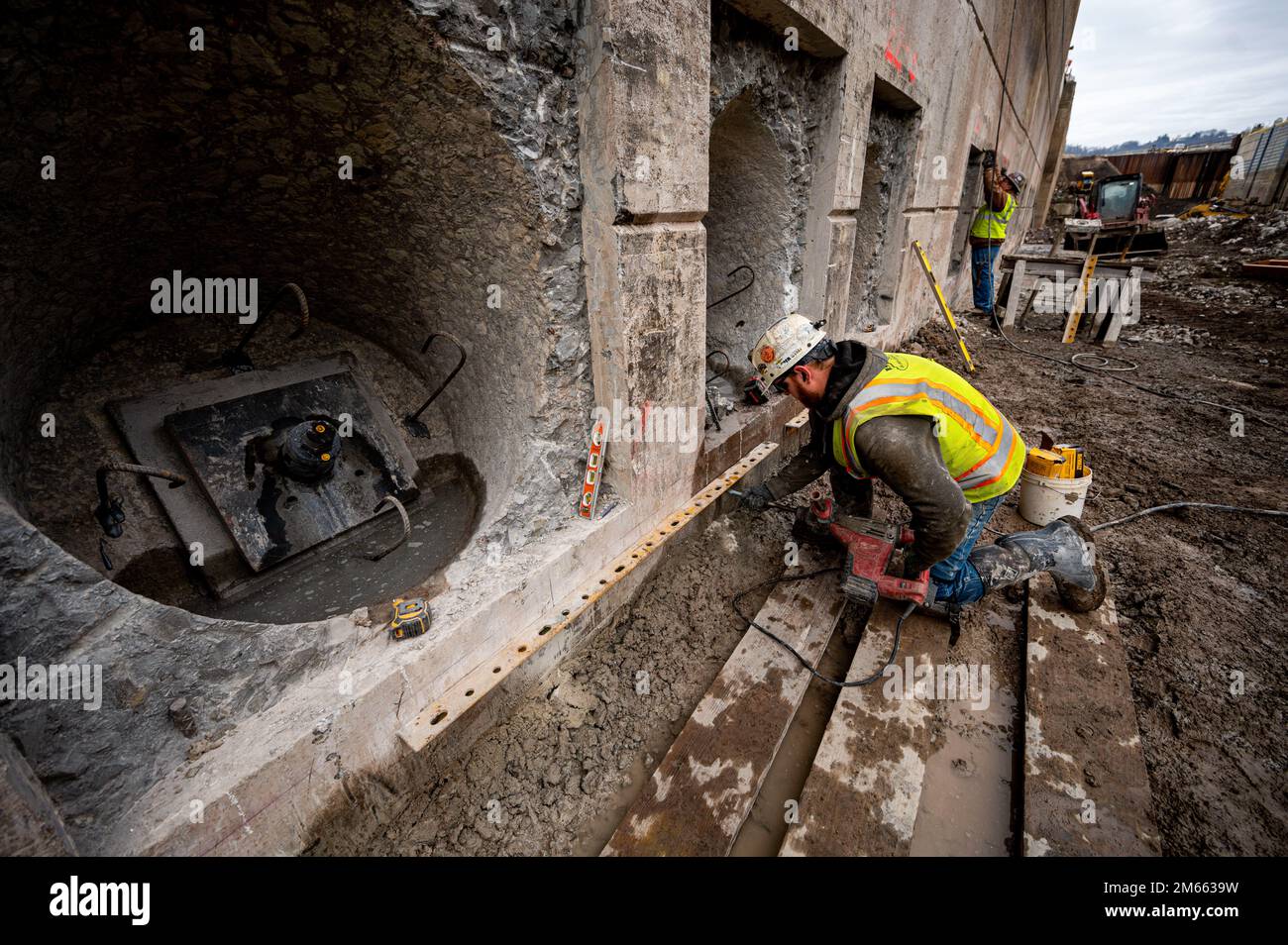 Jeremy Clevenger, a carpenter, drills holes to prepare a concrete form ...