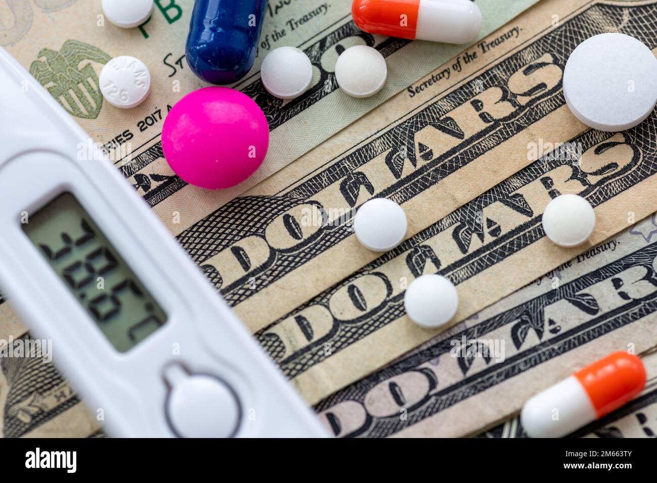 Close up of medicine and a thermometer on top of Dollar bills. Heath ...