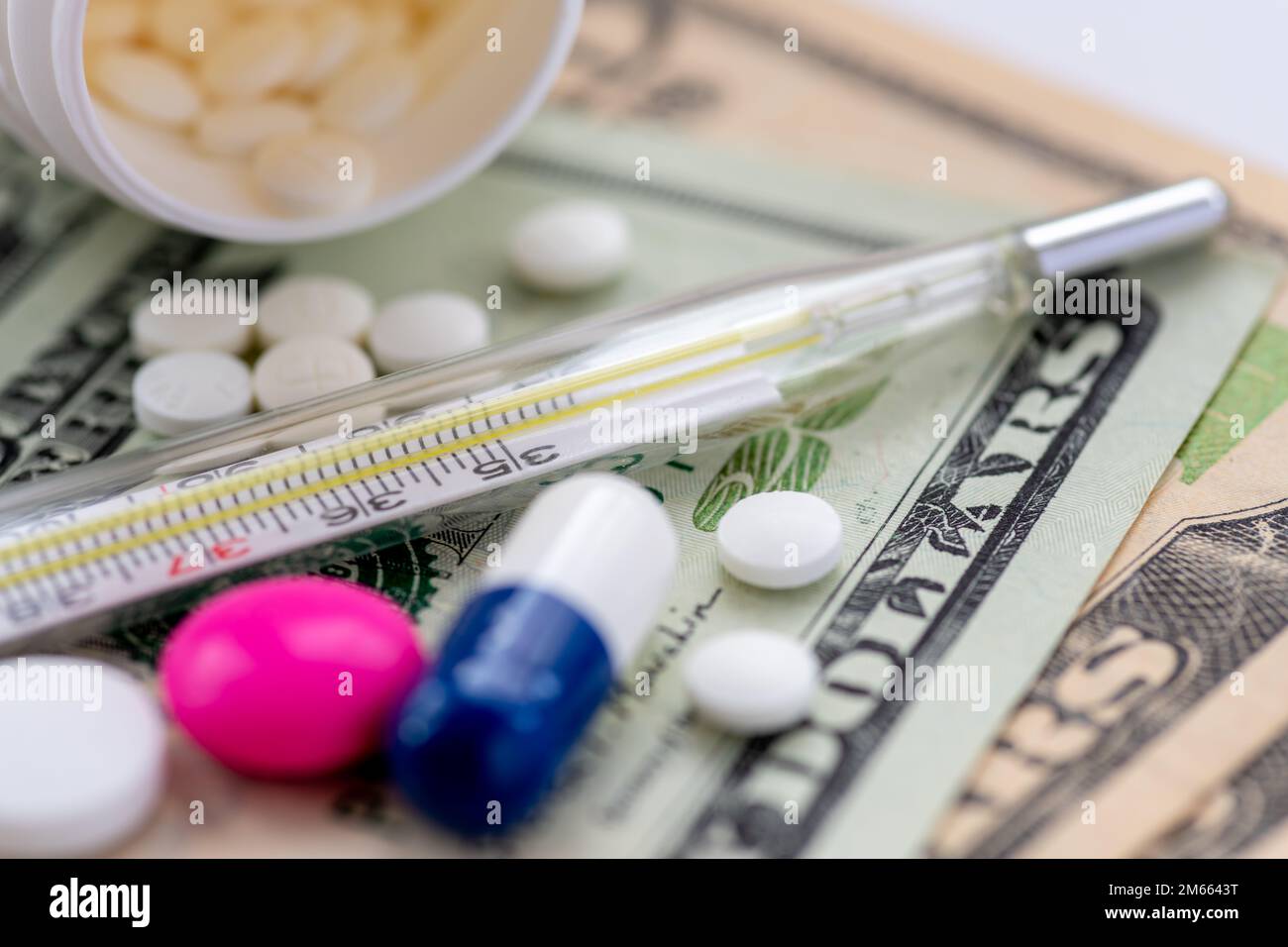 Close up of medicine and a thermometer on top of Dollar bills. Heath ...