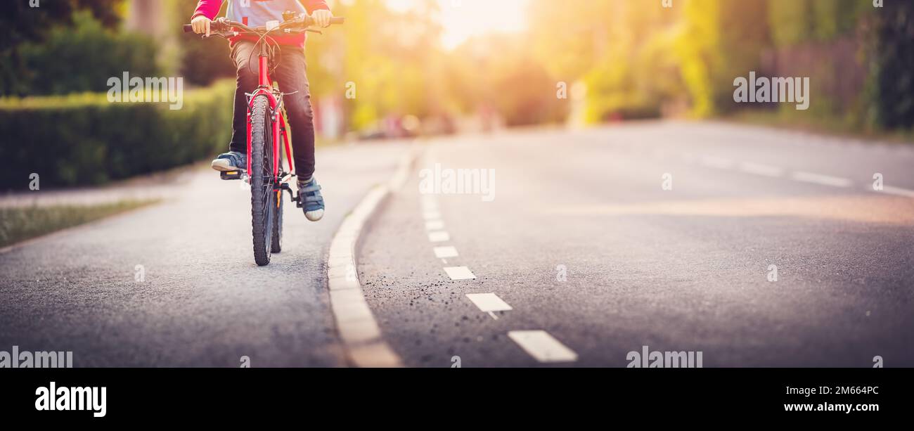 Boy riding a bike on the sidewalk along asphalt road Stock Photo - Alamy
