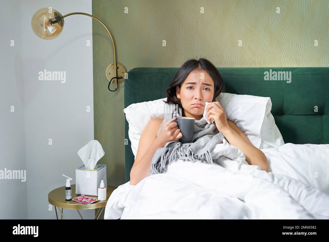 Health and people. Asian girl lying in bed, feeling sick, sneezing and ...