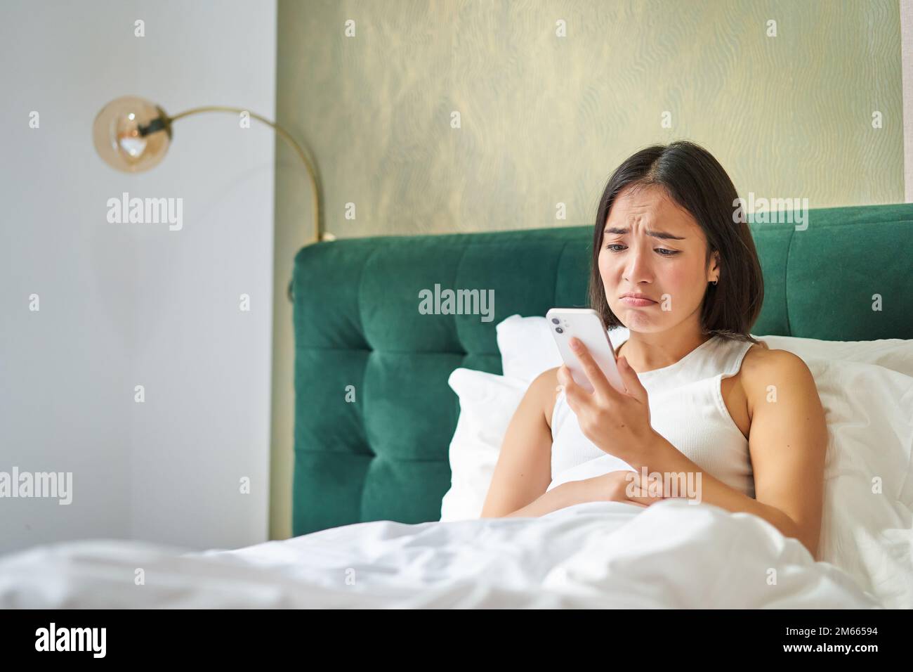 Portrait of concerned asian woman holding mobile phone, receive bad ...