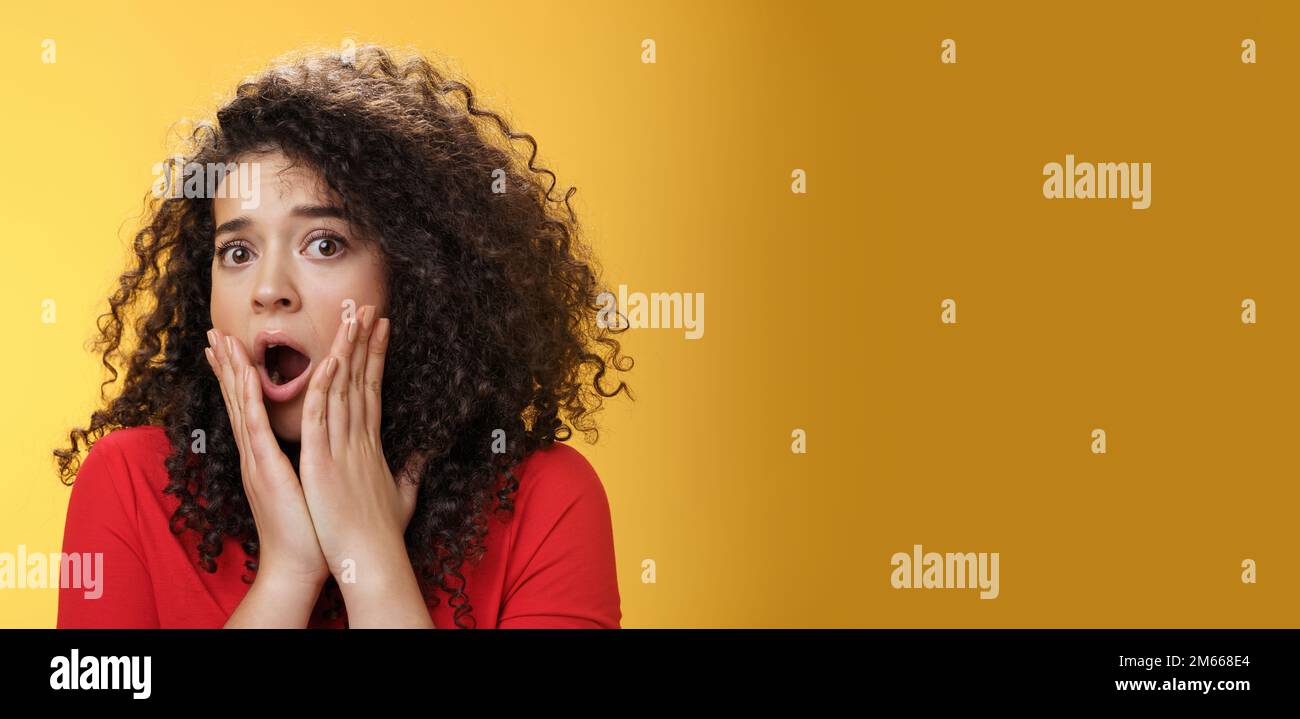 Indoor shot of shocked female drama queen with curly hair gasping in ...