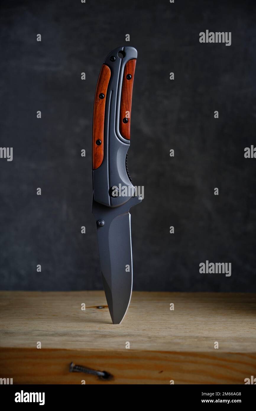 Folding knife for survival stuck wooden beam, on dark background Stock ...