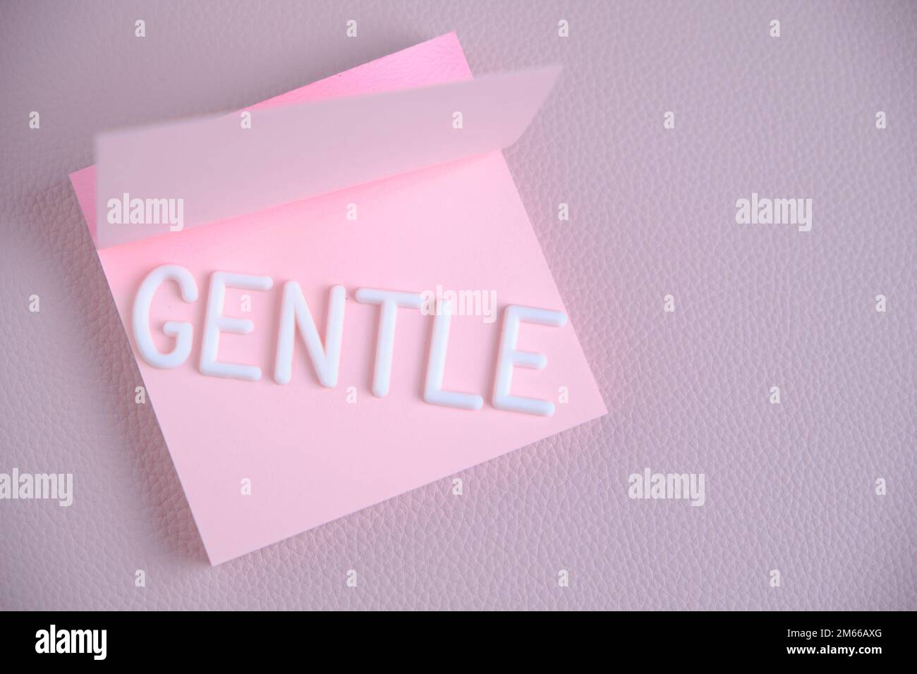 Word gentle laid out white letters pink piece paper.Concept tenderness ...