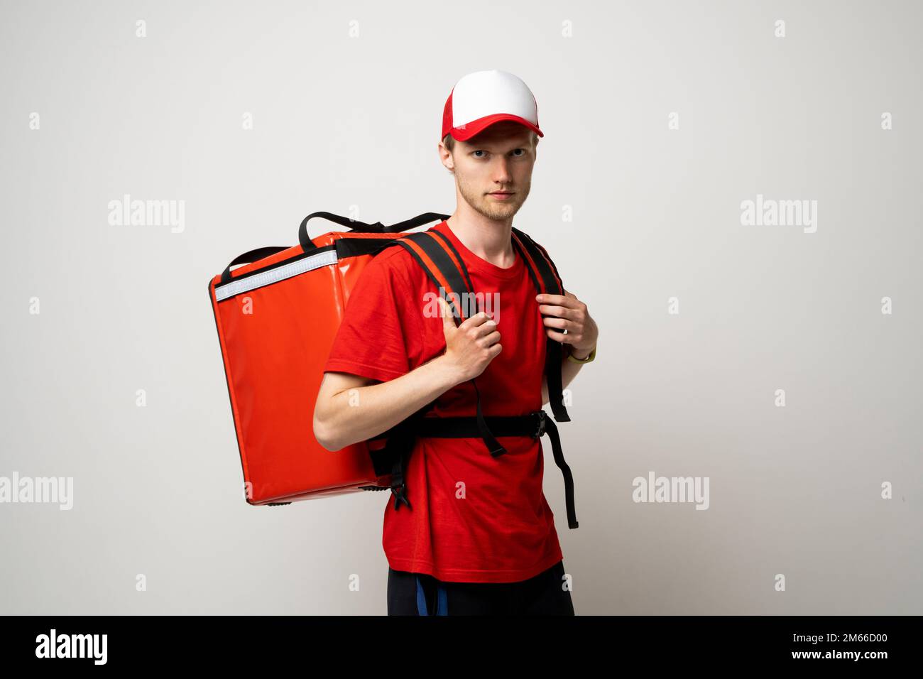 Young courier delivery man in red uniform with thermo backpack on white ...