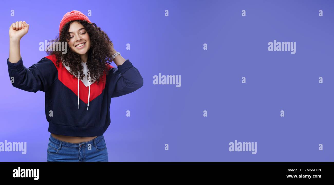 Girl delighted and carefree dancing over blue background with closed ...