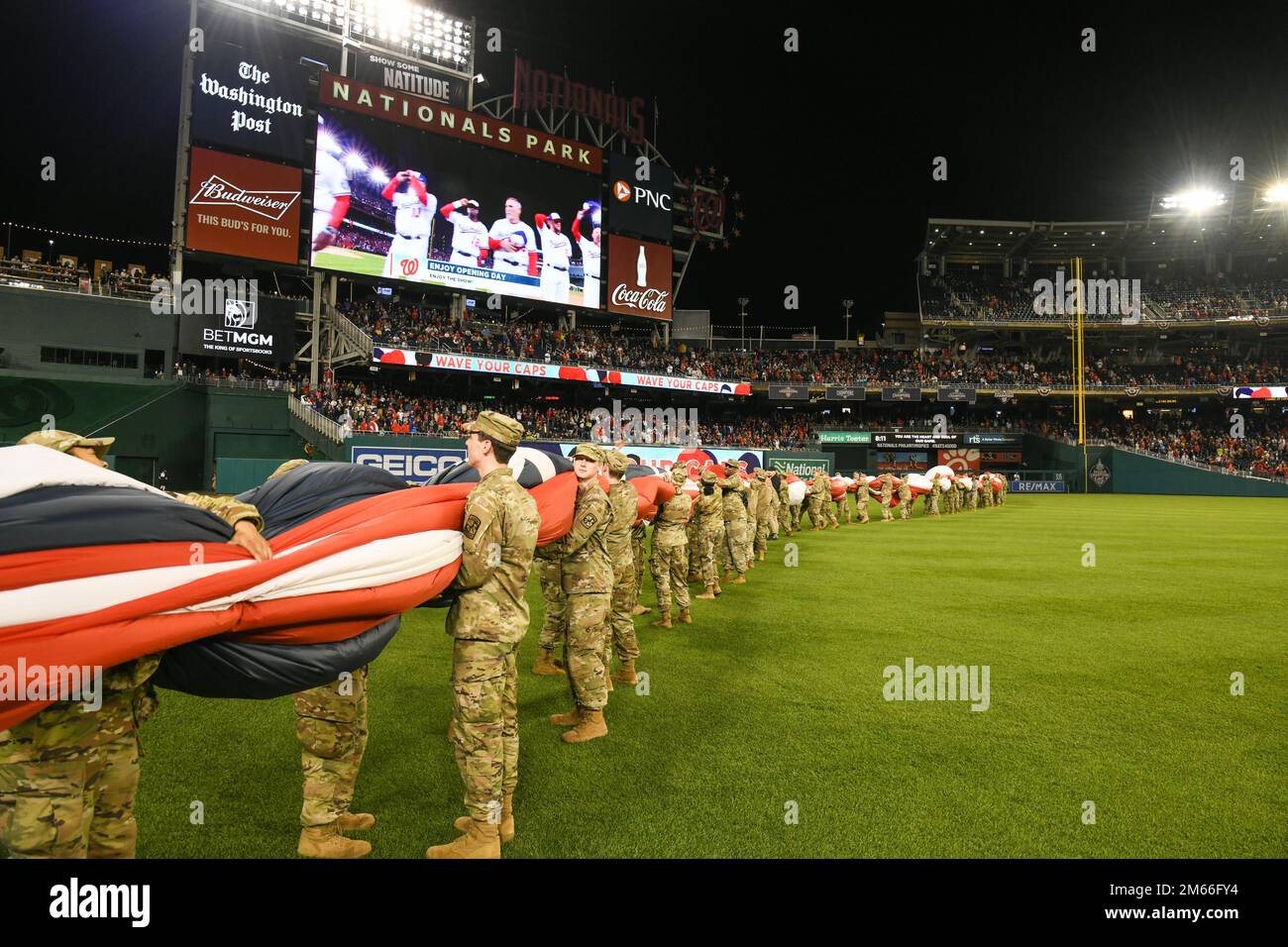Airmen and soldiers of the D.C. National Guard unfurl a giant U.S. flag ...