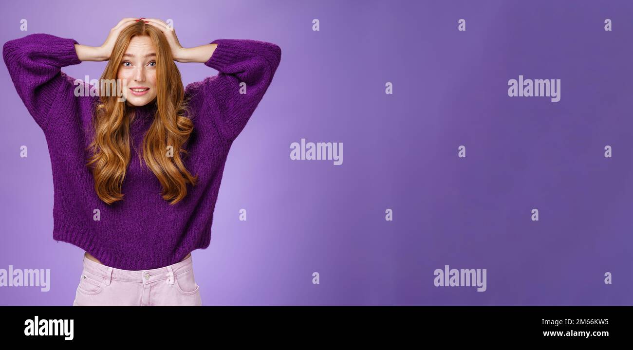 Cute european redhead 20s woman acting nervous, holding hands on head ...