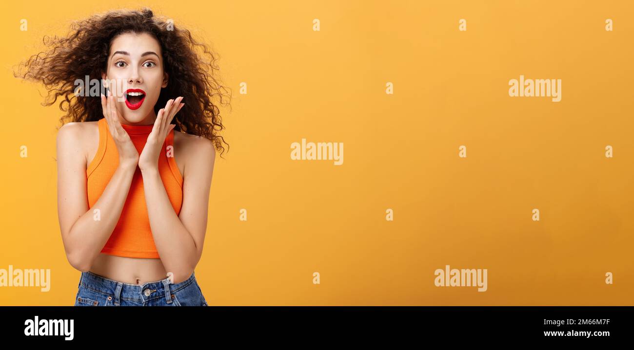 Waist-up shot of charmed enthusiastic attractive female with curly ...