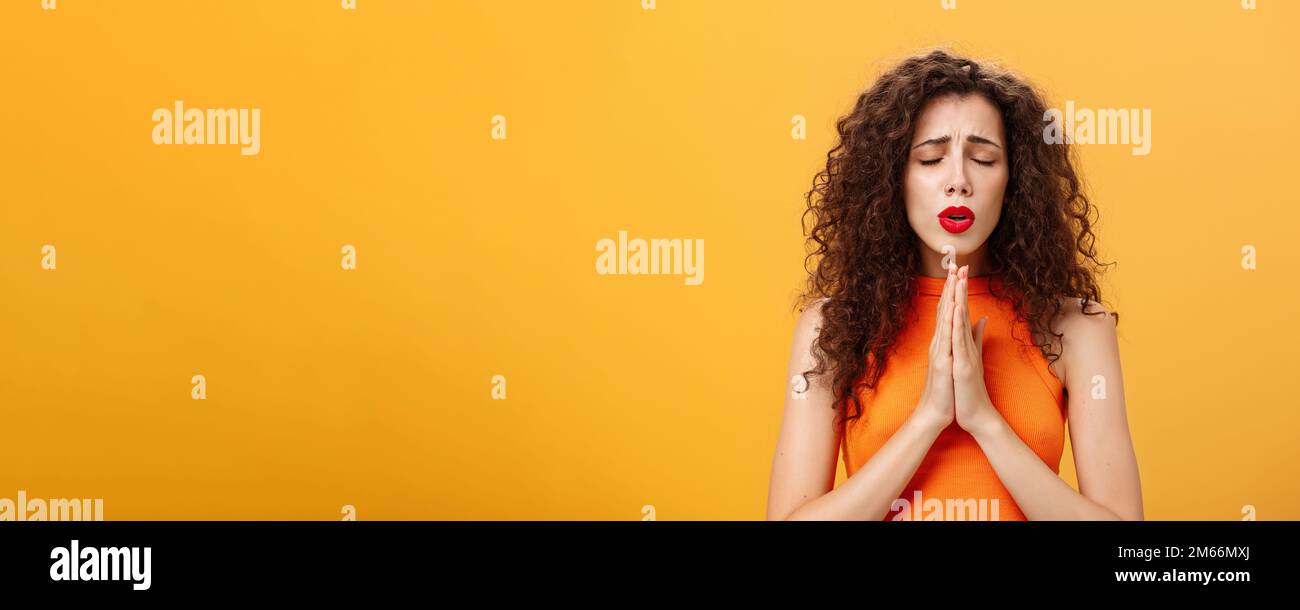 Nervous and concerned woman with curly hairstyle feeling hopeful ...