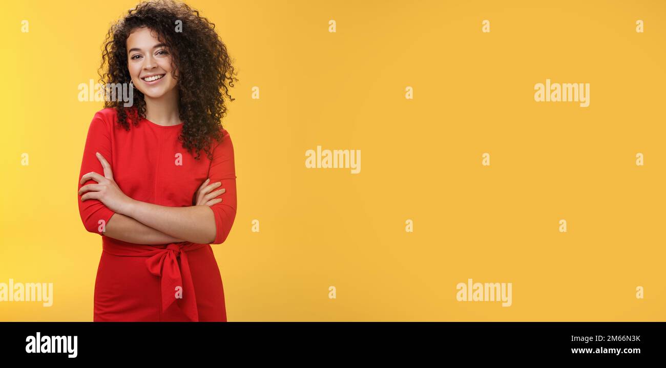 Confident charismatic young curly-haired woman in casual red dress ...