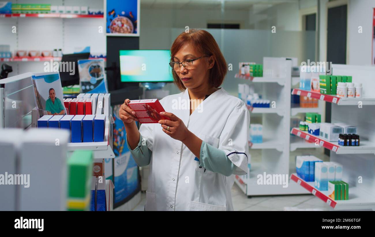 Pharmacist looking at cardiology pills on drugstore shelves, working ...