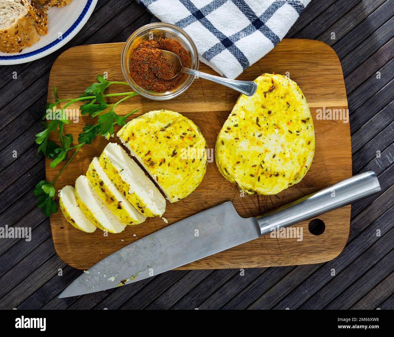 Sliced fried cottage cheese with cumin and turmeric on wooden board ...