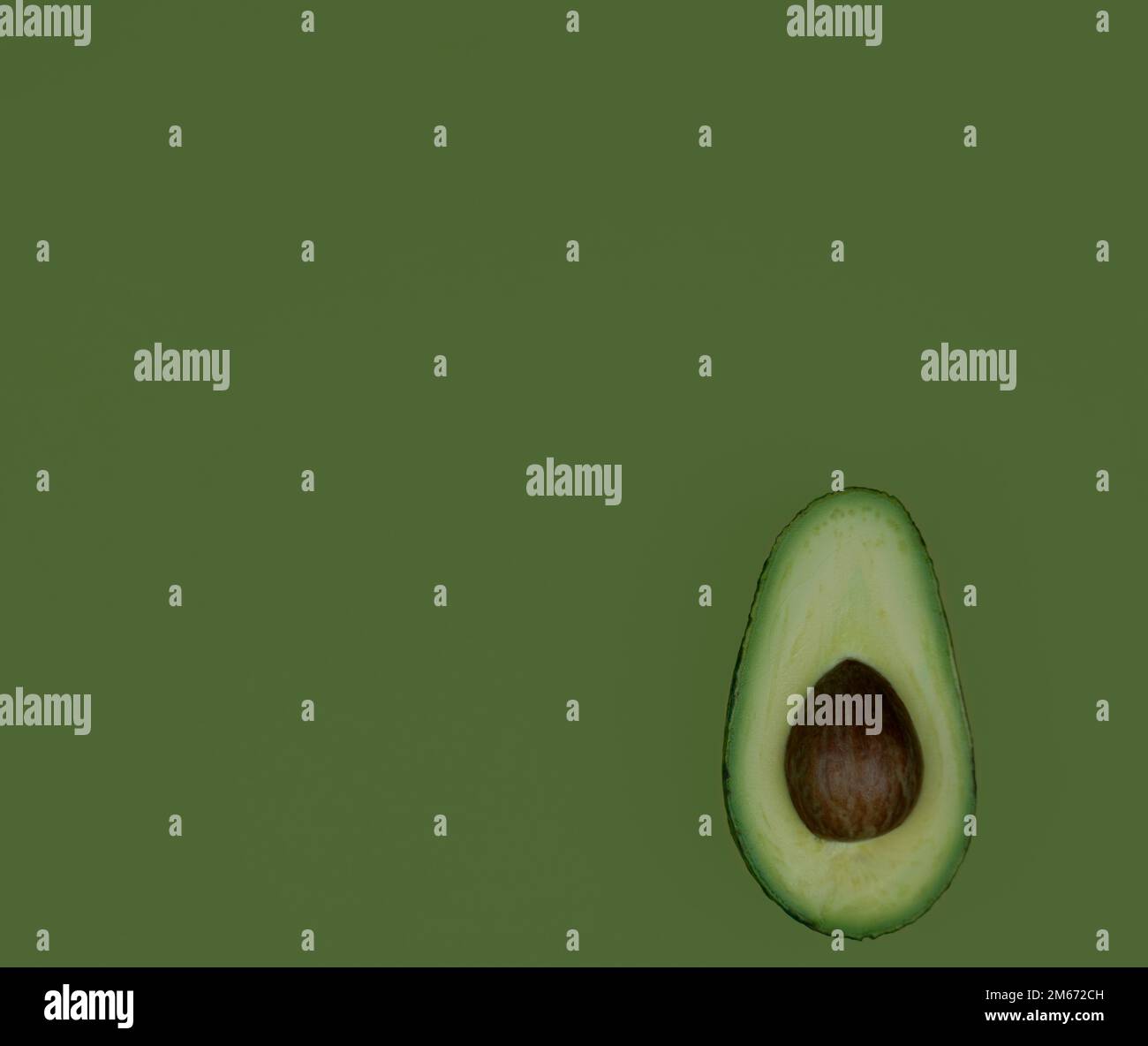 Avocado fruit half on green background. Green avocado, minimal flat lay ...