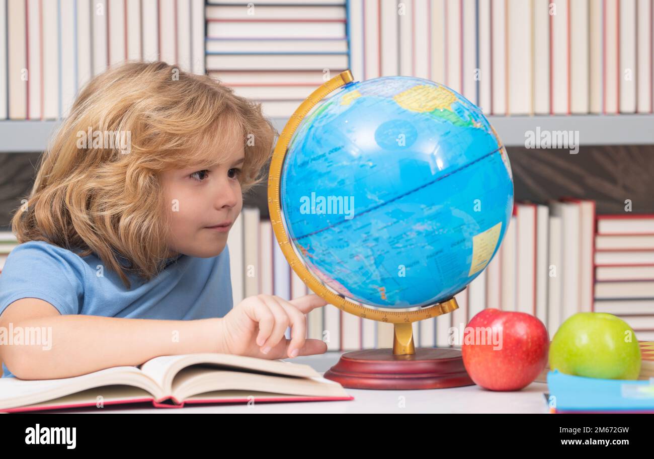 School pupil looking at globe in library, geography lesson. School and ...