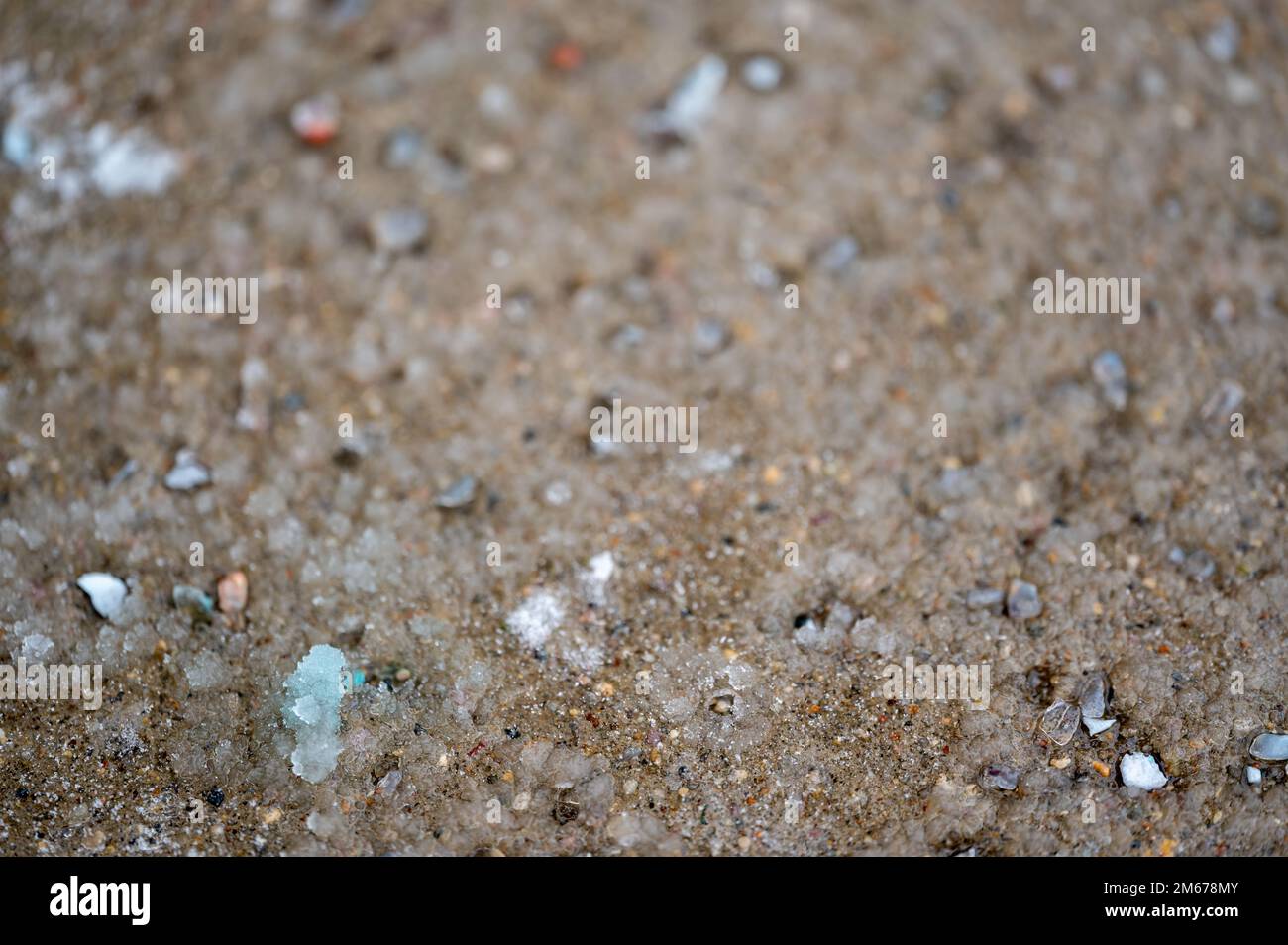 macro ground level closeup view of rock salt ice-melt on concrete with ...