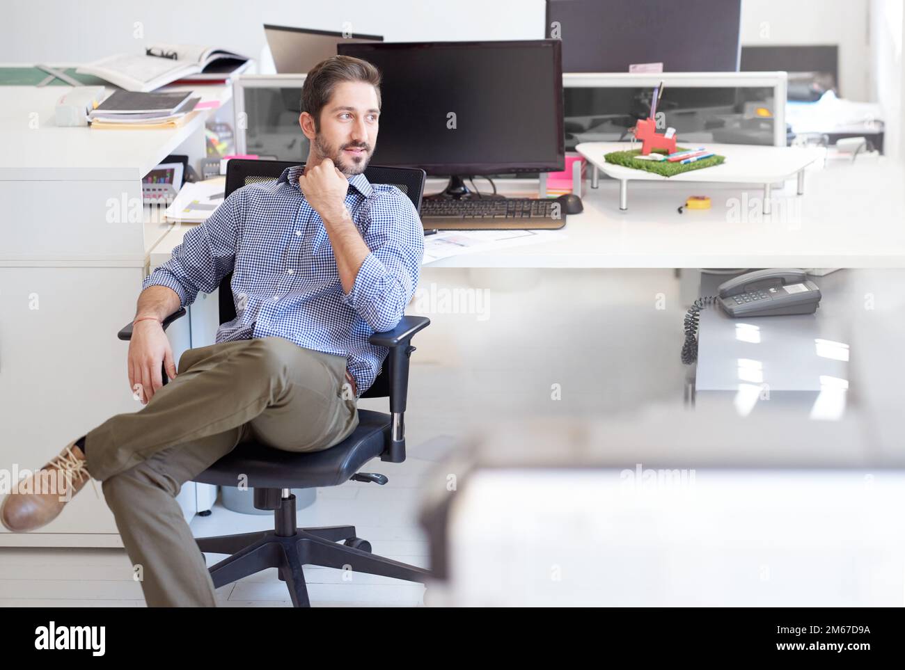 Full of creative ideas. a young designer sitting at his workstation in ...