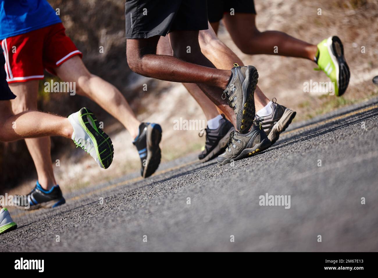 Gathering momentum. the legs of a group of men running a road race ...