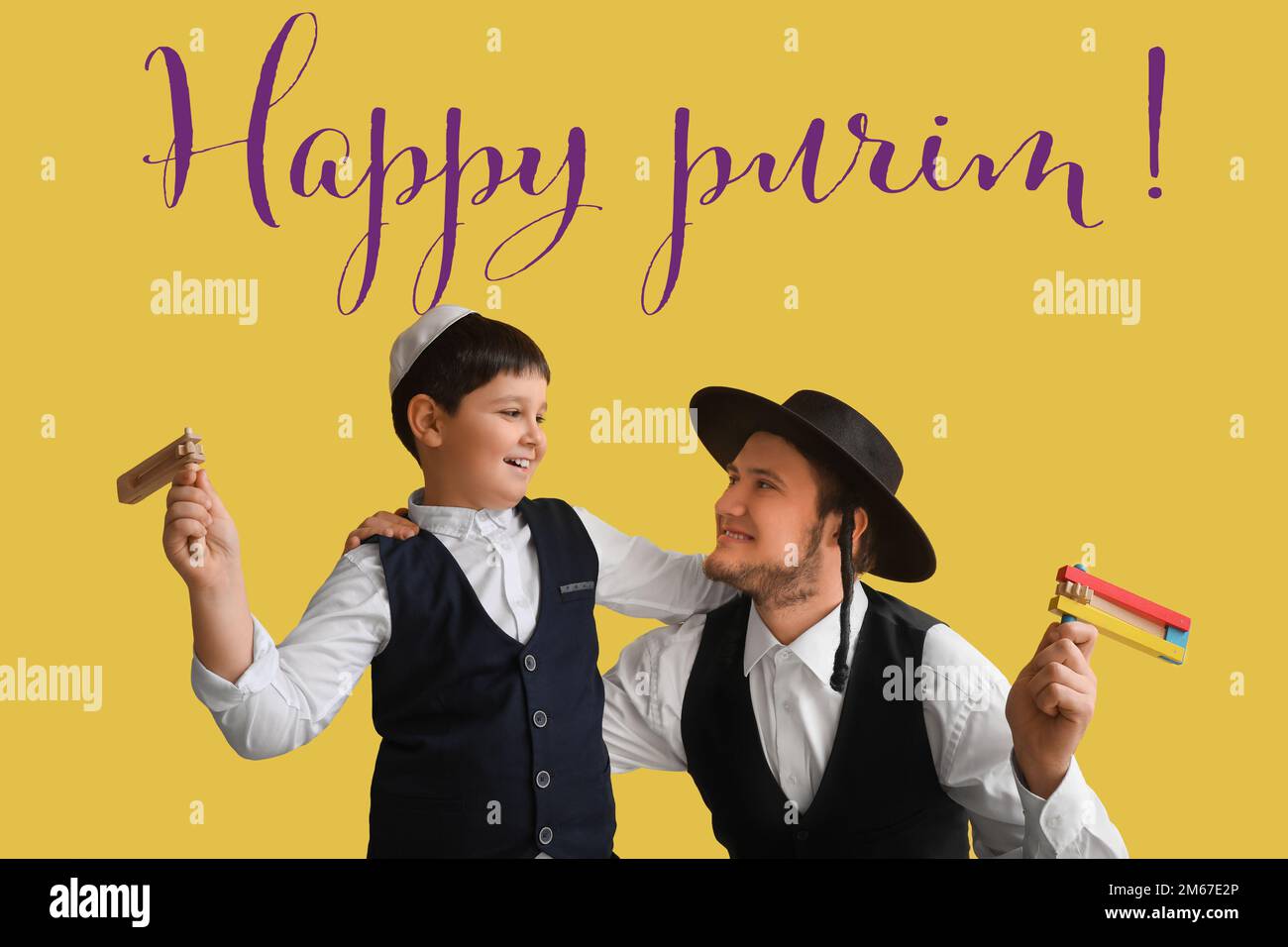 Happy Jewish man and boy with graggers for Purim holiday on yellow ...