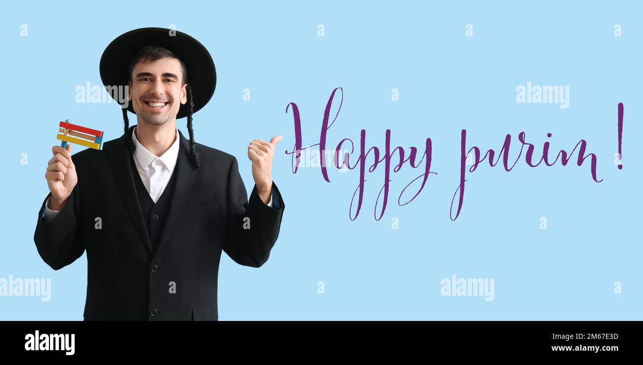 Happy Jewish man with Purim rattle on light blue background Stock Photo ...