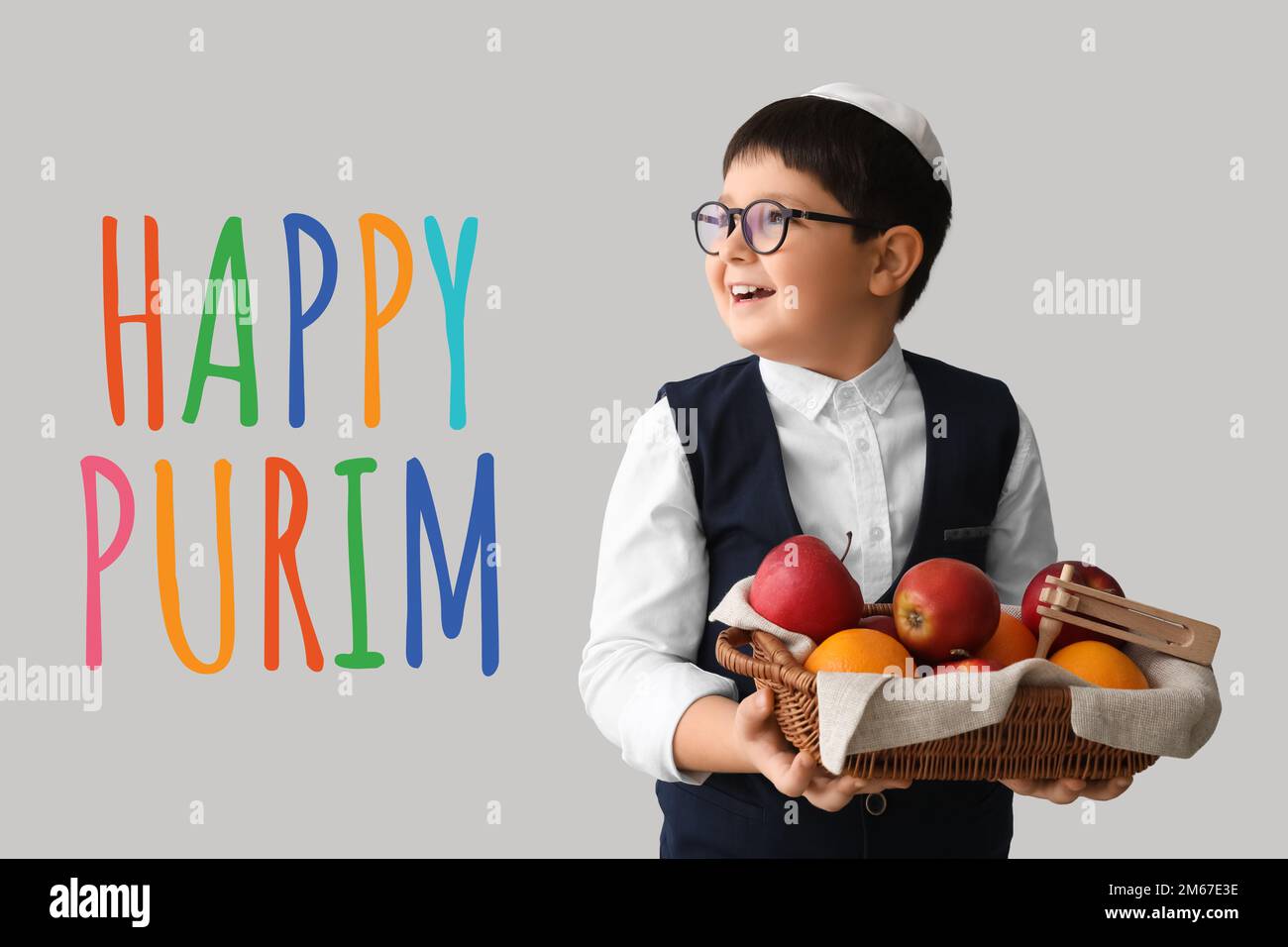 Little Jewish boy with gragger for Purim holiday and fruits in basket ...