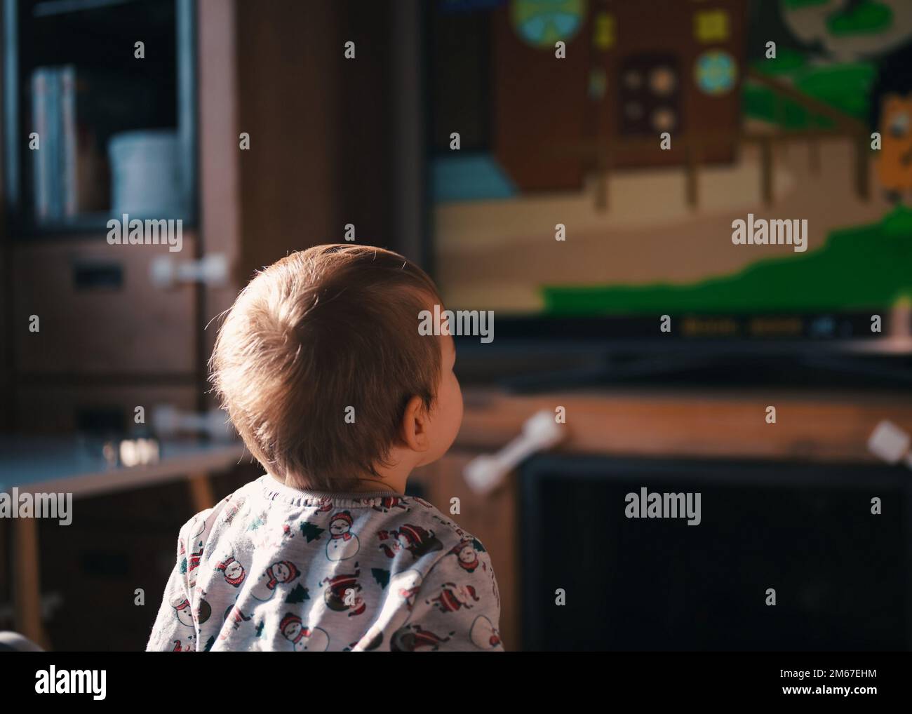 Rear view of little toddler sitting and watching television Stock Photo ...