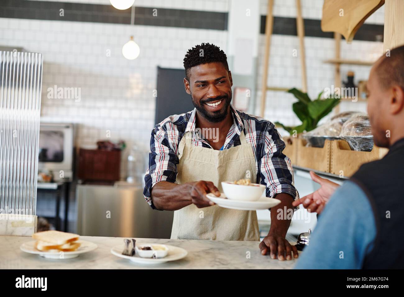 Serving one of his regulars. a young man serving a customer at a cafe ...