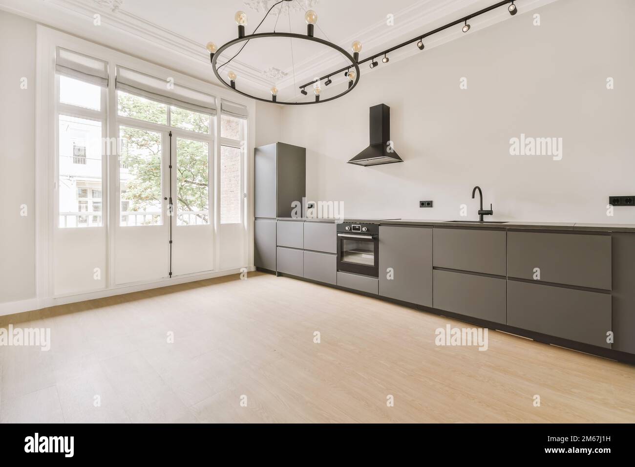 an empty kitchen with wood flooring and white walls in a large window ...