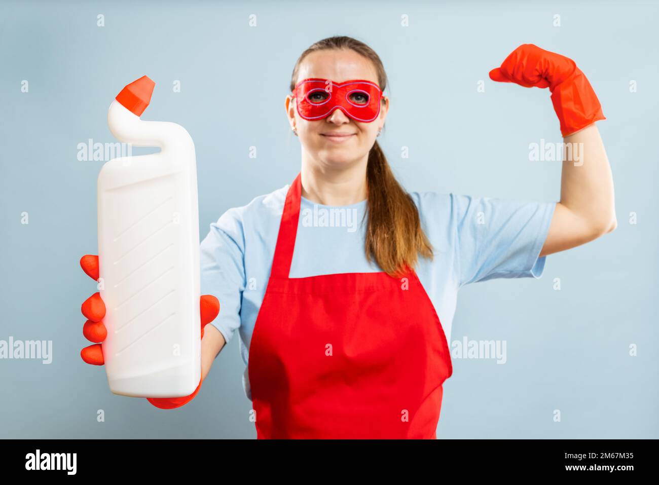 Woman in red mask, rubber gloves and apron holding cleaning agent ...