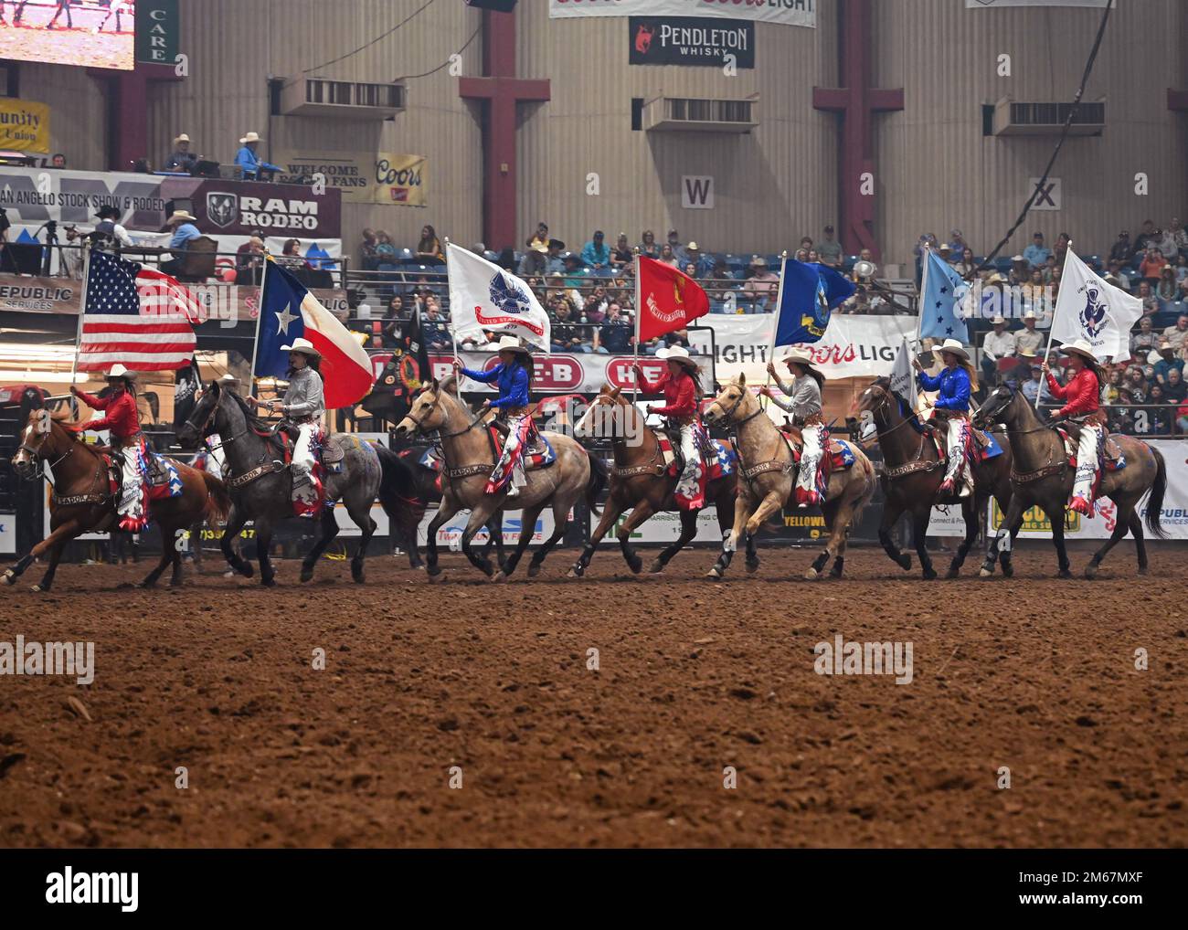 Rodeo participants ride around the ring carrying flags during Military ...